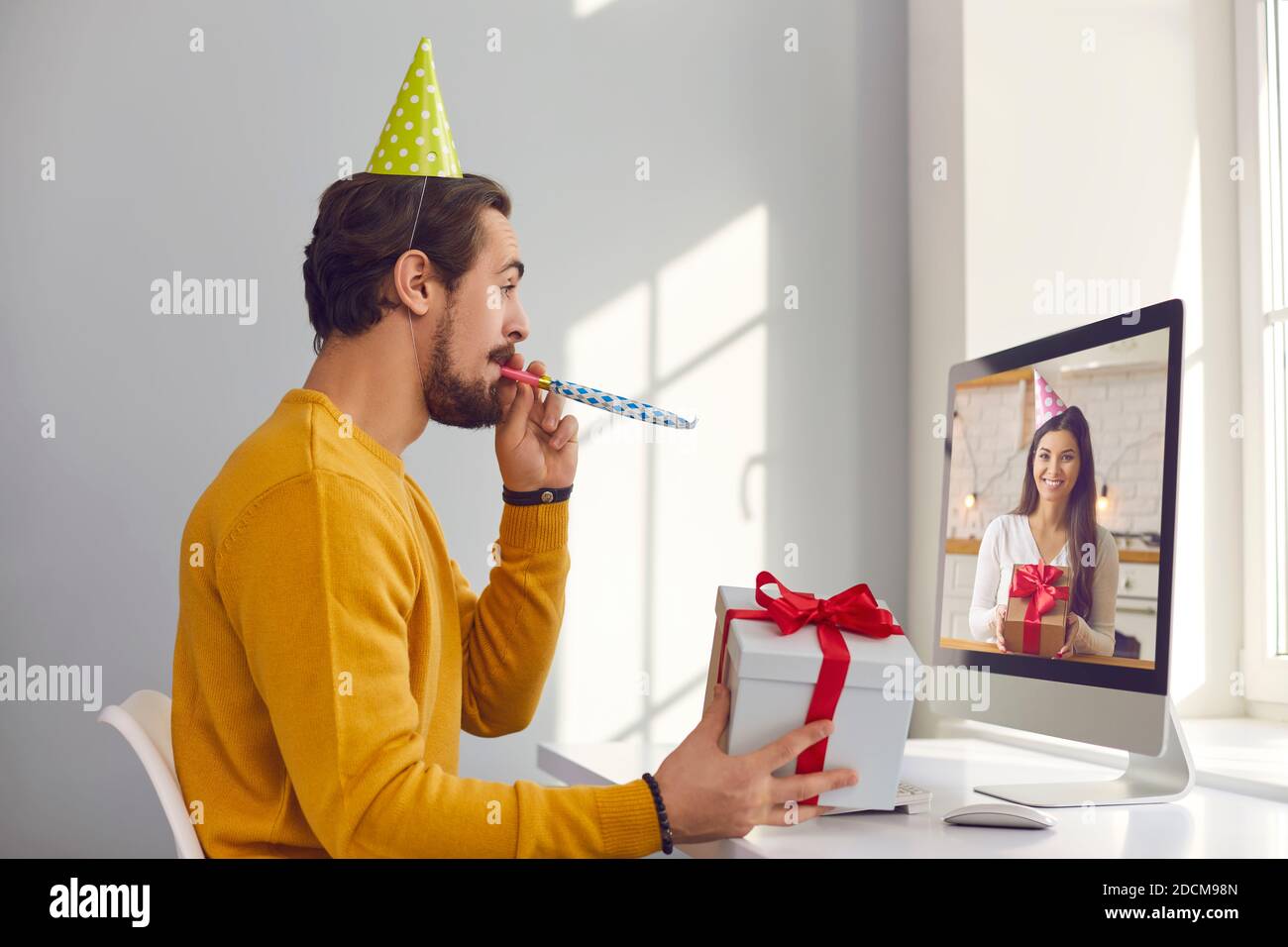 Happy young man sitting at computer and having virtual party with his ...