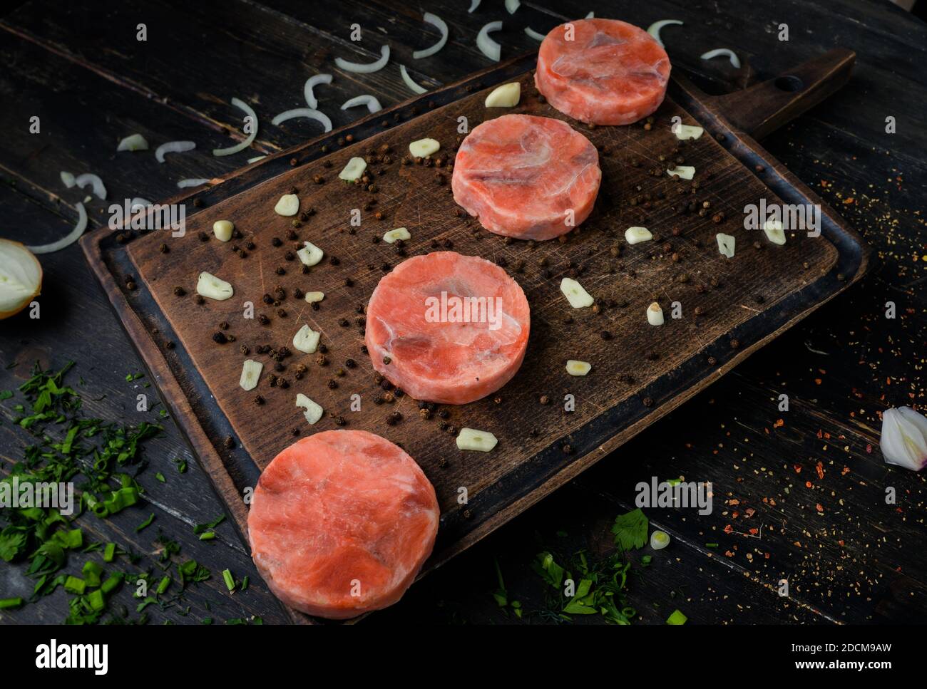 Raw fresh salmon medallions with garlic and onion on wooden cutting ...