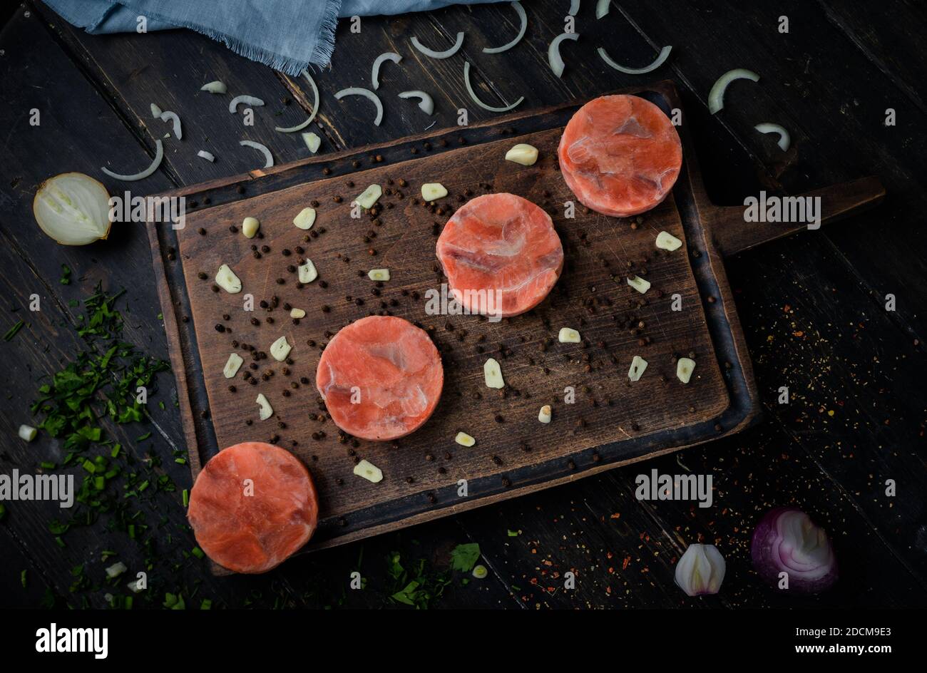 Raw fresh salmon medallions with garlic and onion on wooden cutting ...