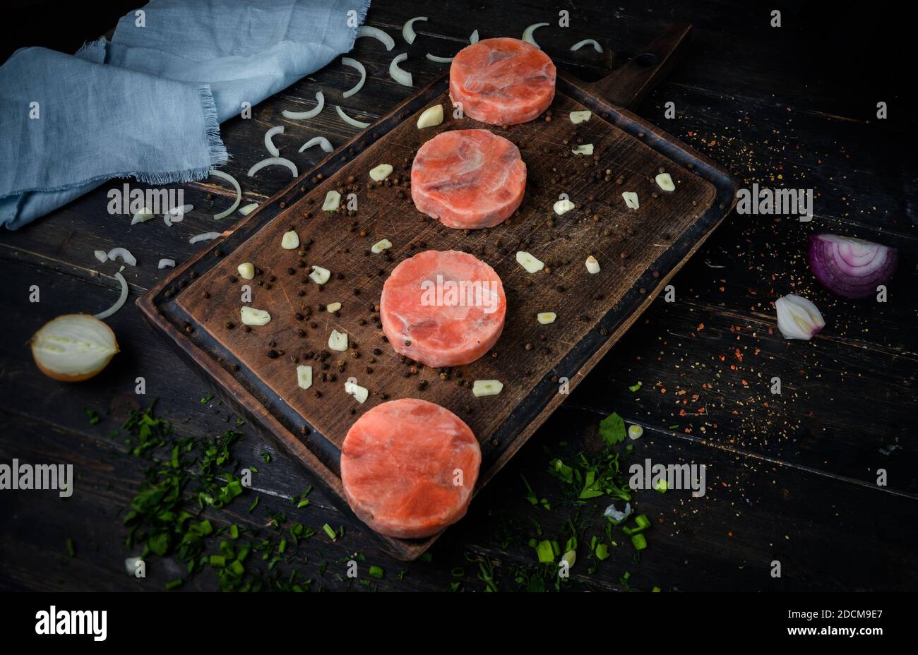 Raw fresh salmon medallions with garlic and onion on wooden cutting ...