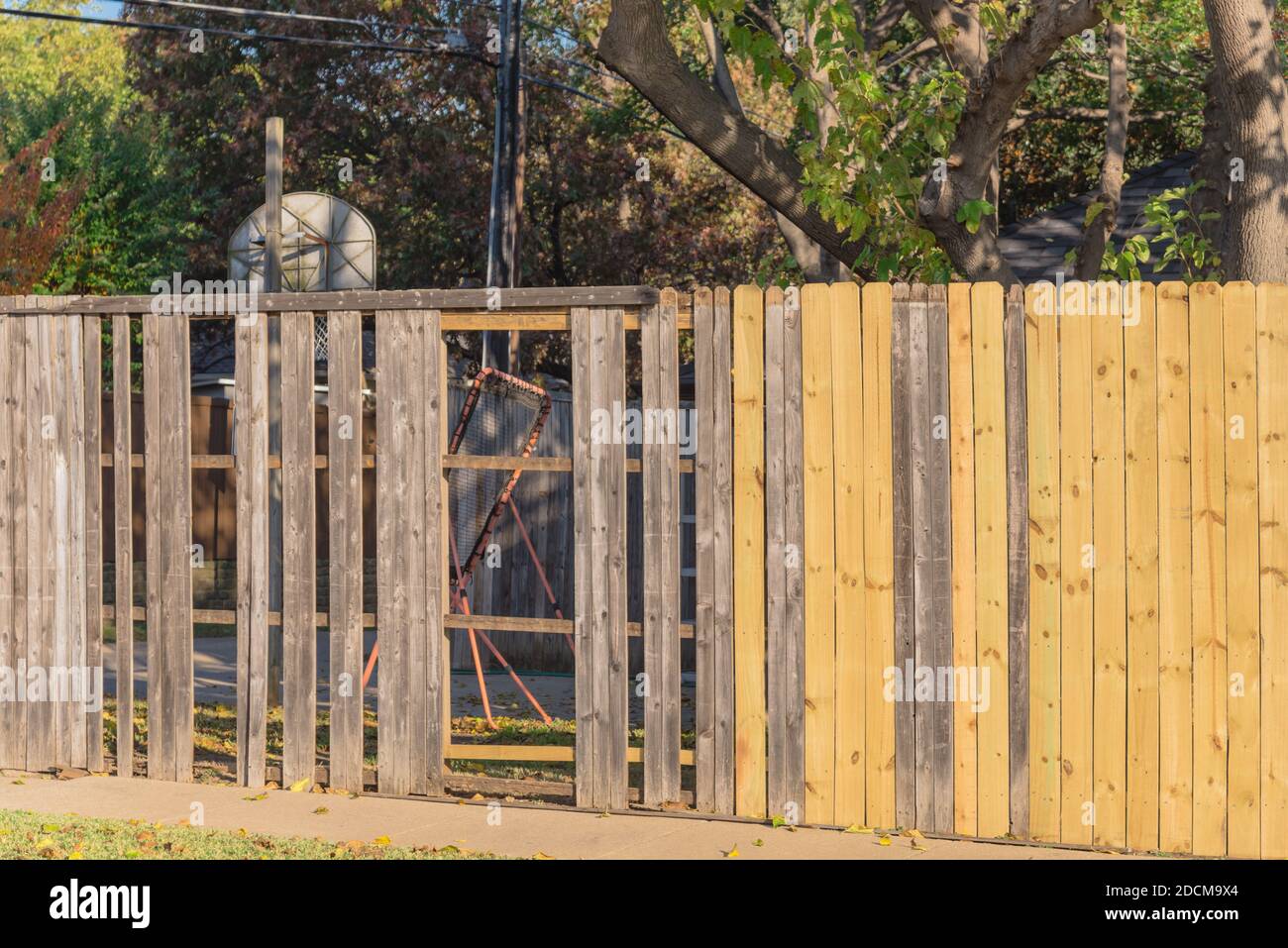 Close-up new wooden fence near collapsed aged slats in backyard of ...