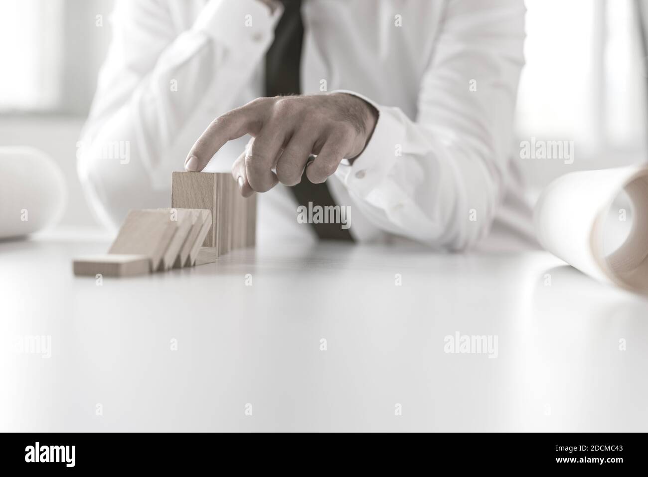Man preventing dominoes from crumbling on a white office table, retro ...