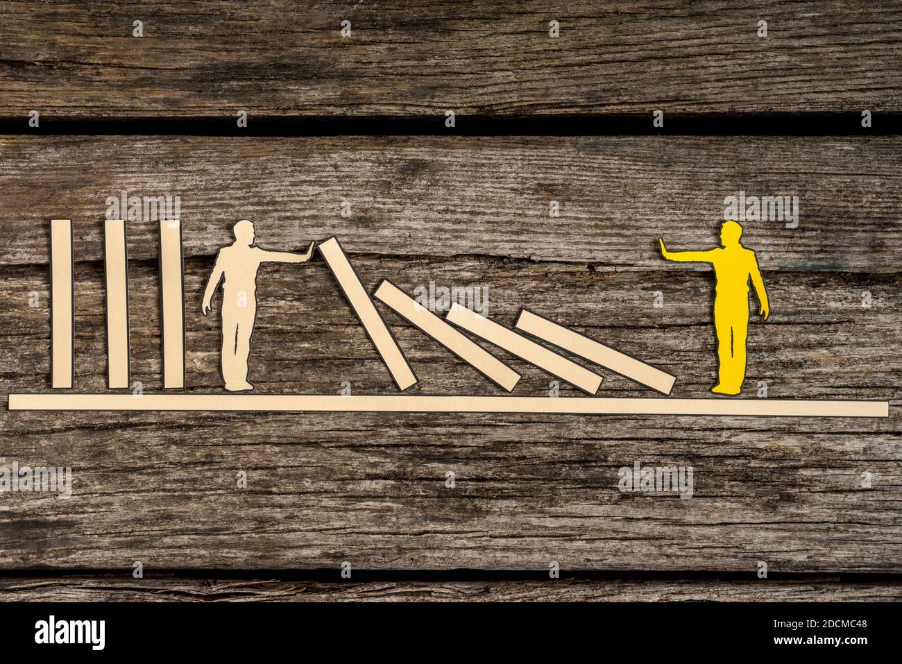 White silhouette cutout of a man holding up fallen blocks as yellow ...