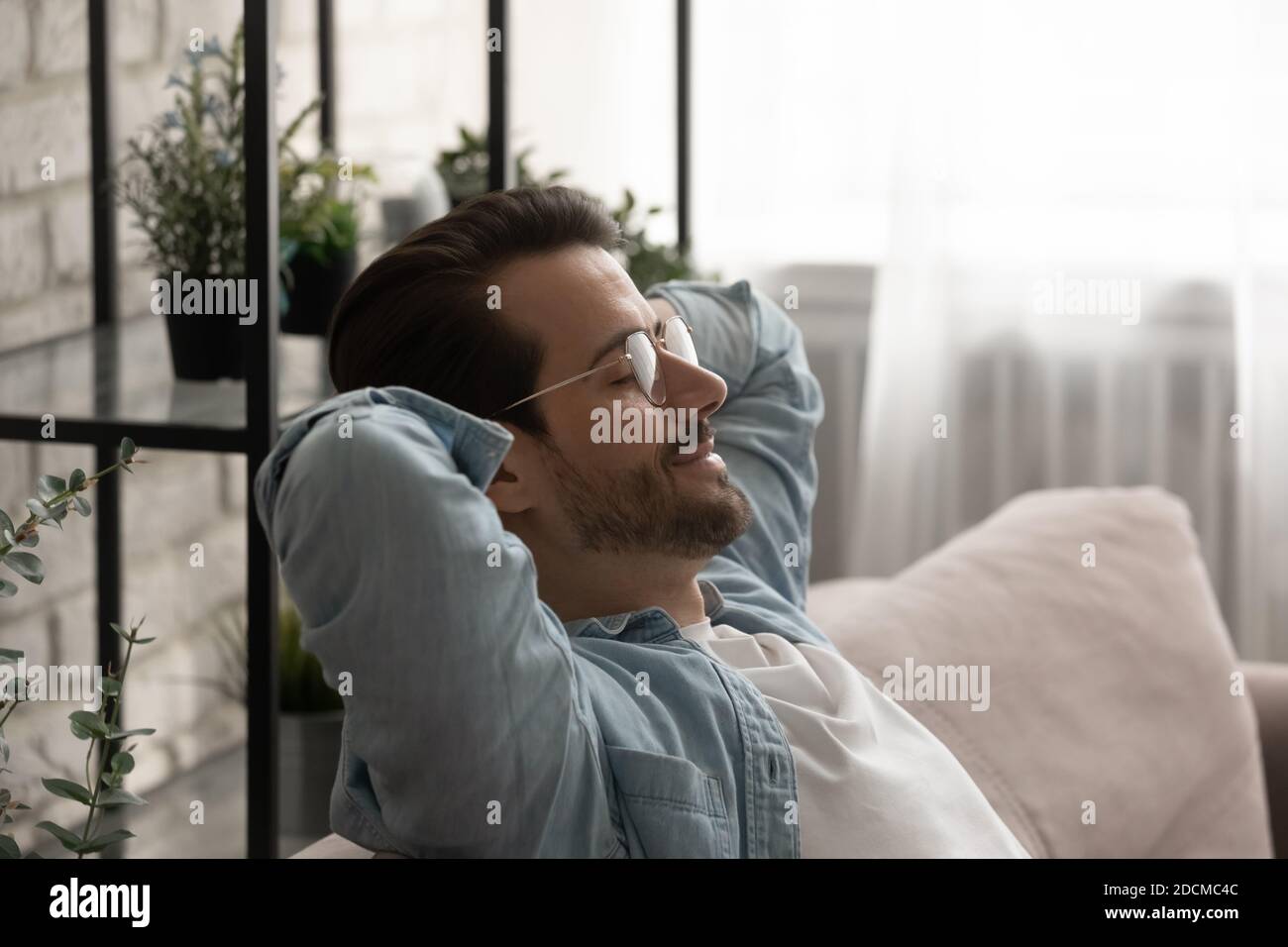 Calm serene young 30s man resting on sofa Stock Photo - Alamy