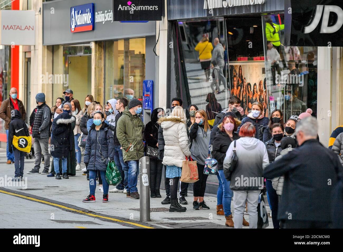 Shoppers wait in queues to enter stores in Cardiff, where restrictions ...