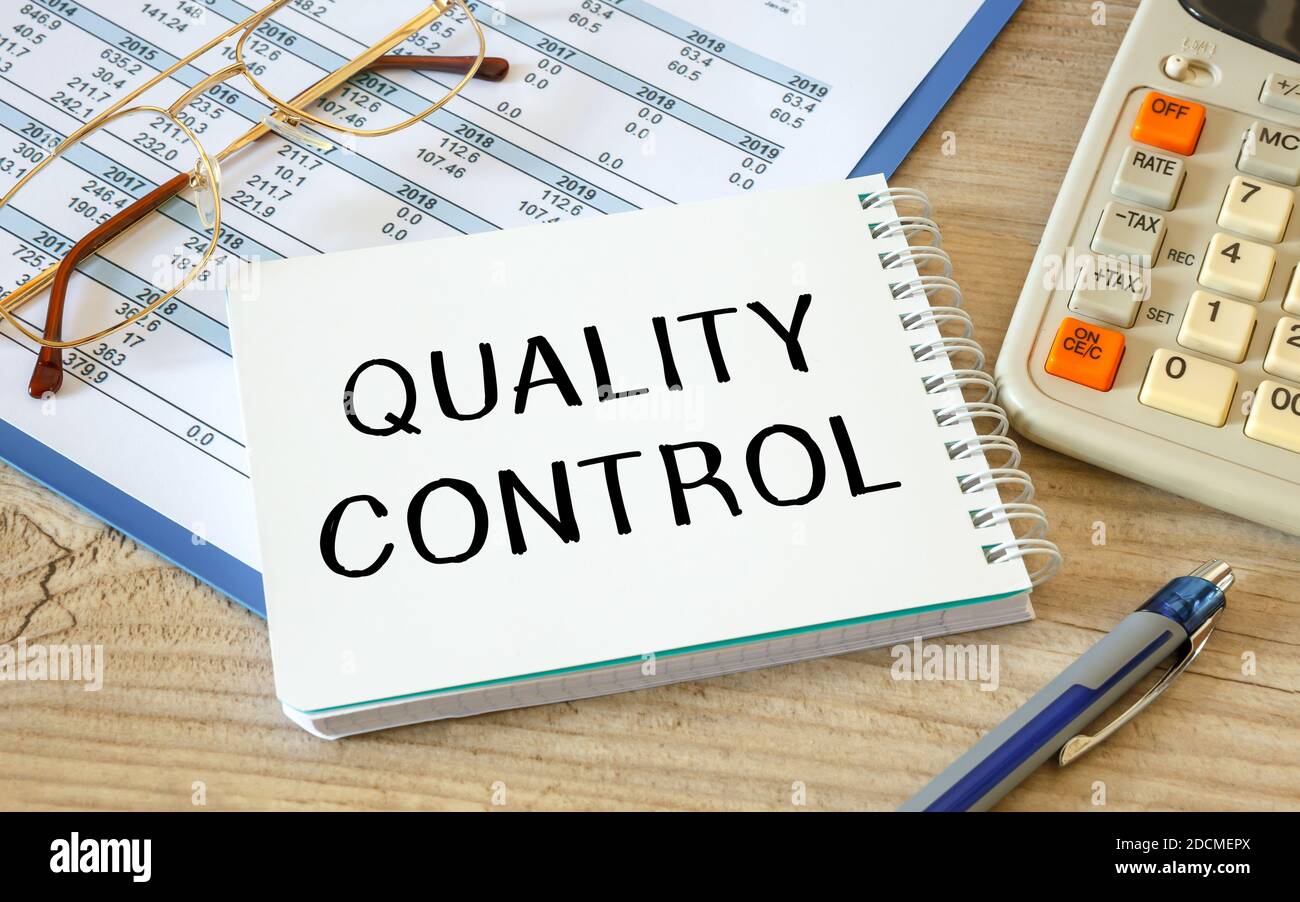 Quality Control is written on a notepad on an office desk with office ...