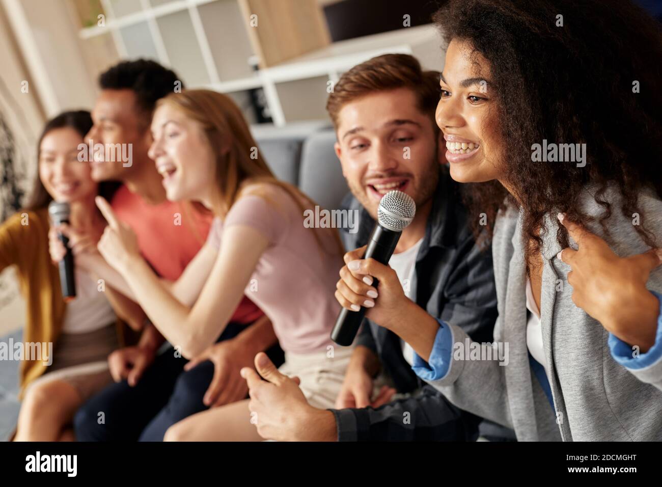 Friends and music. Joyful friends looking excited while playing karaoke ...