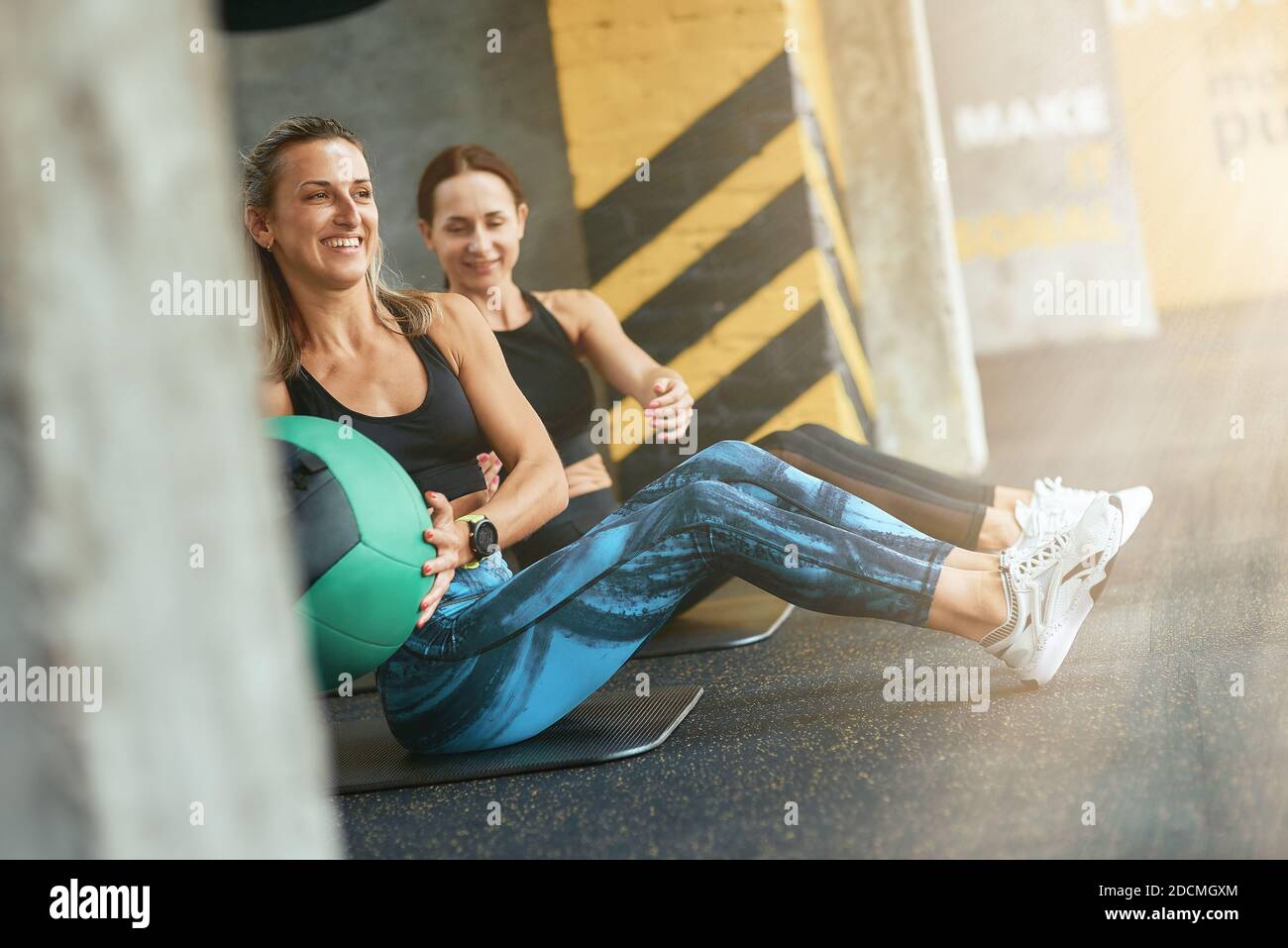 Two young happy athletic women in sportswear exercising with fitness ...