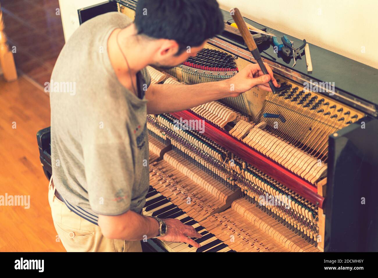 Piano tuning process. closeup of hand and tools of tuner working on ...