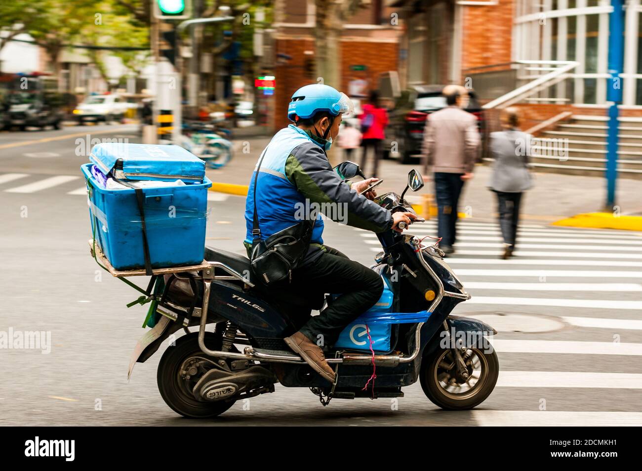 An Eleme delivery rider using his phone while riding his scooter at the ...