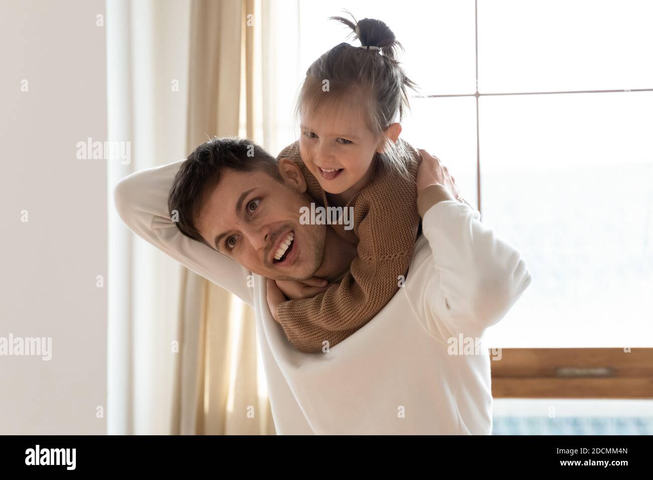 Cute girl piggyback daddy play together at home Stock Photo - Alamy