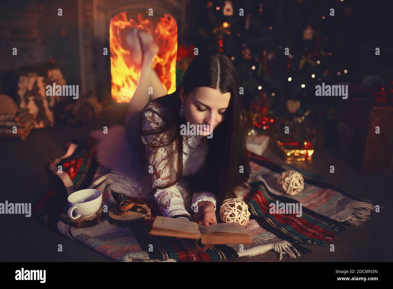 young girl reading a book on a winter day by the fireplace Stock Photo ...