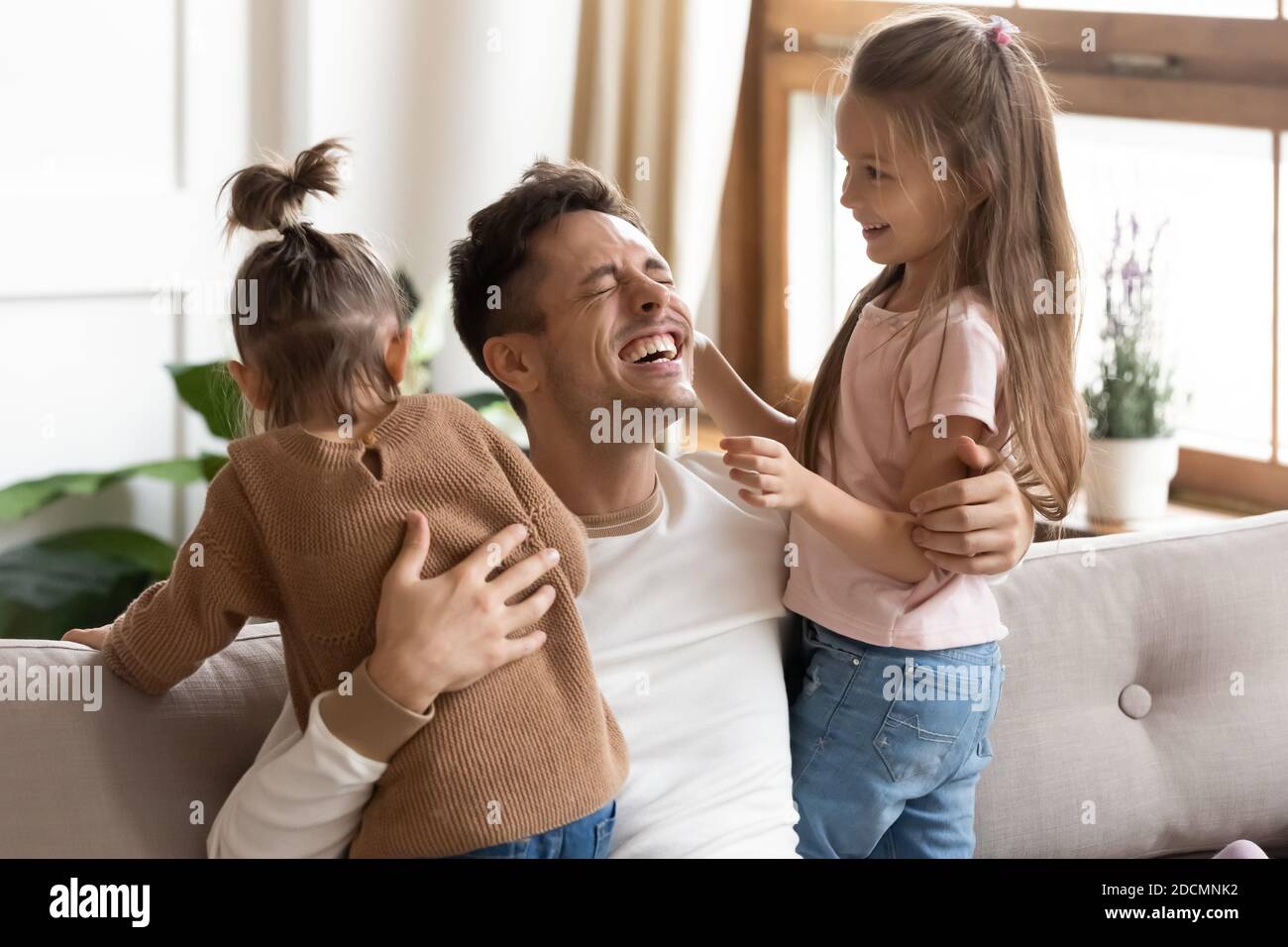 Laughing father spend funny pleasant time with two little daughters ...
