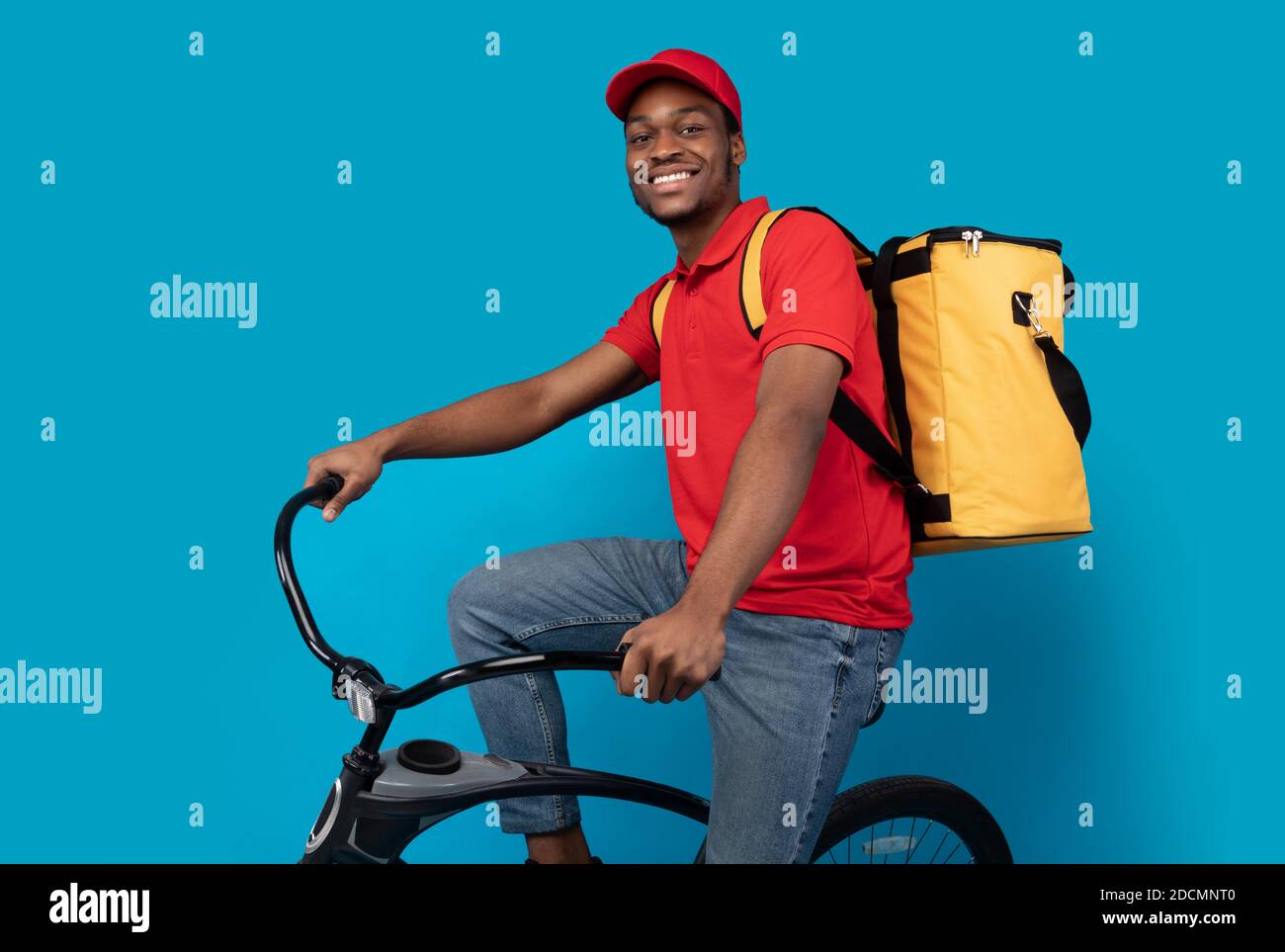 Smiling delivery delivery man riding bicycle at studio Stock Photo - Alamy