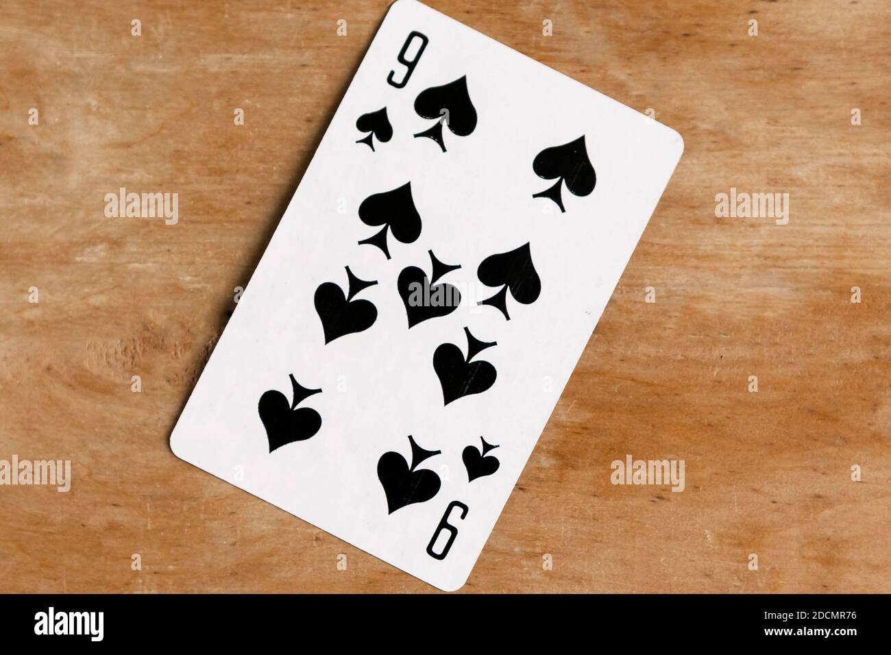 Nine of Spade playing card, wooden background Stock Photo - Alamy