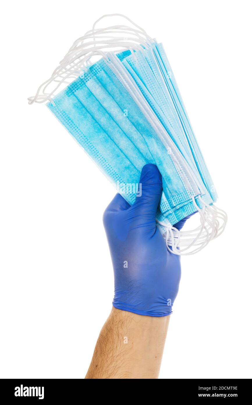 Gloved hand holds a pack of medical masks, isolated on white background ...