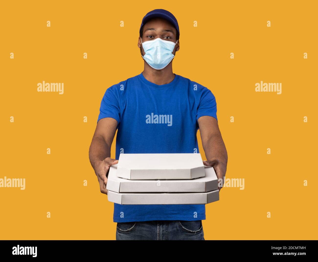 Black delivery man in medical mask holding pizza boxes Stock Photo - Alamy