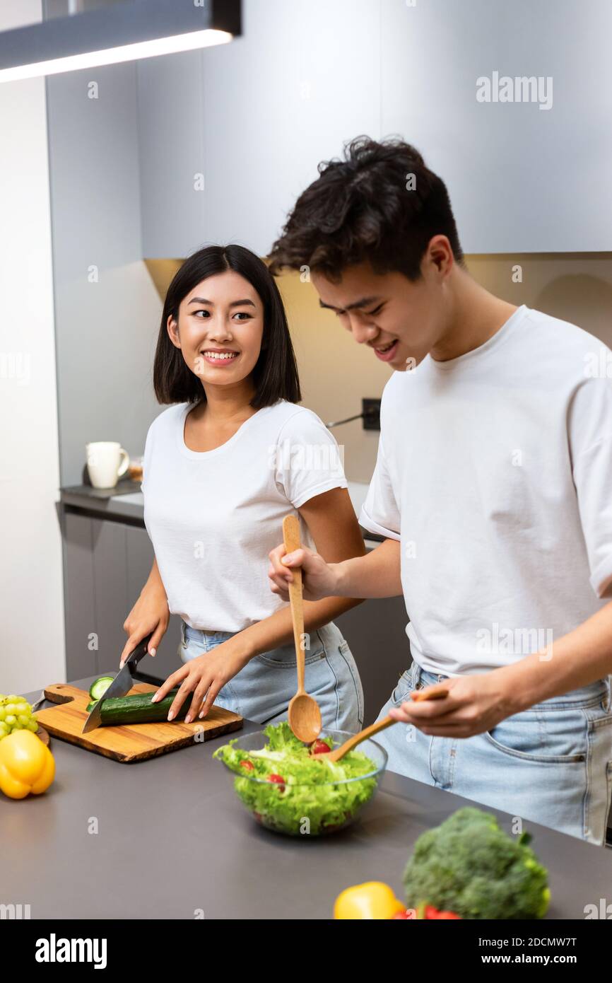 Asian Couple Standing In Modern Kitchen Cooking Together, Vertical ...