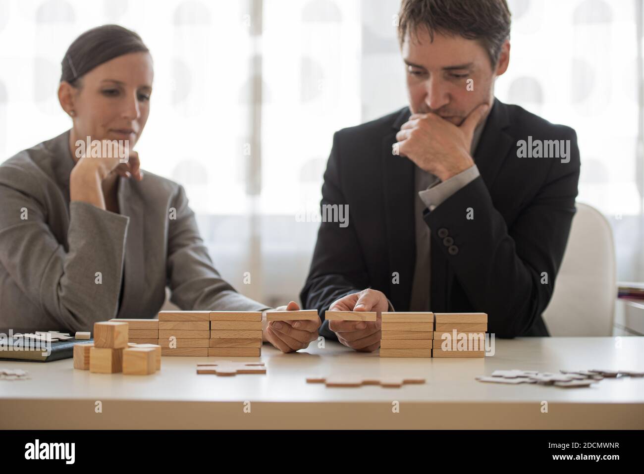 Male and female business partners building a bridge of wooden blocks ...