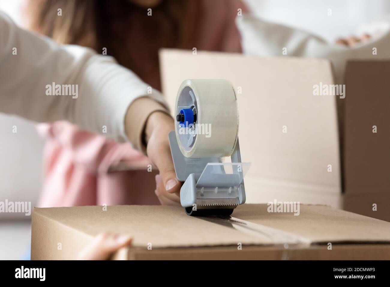 Man holding tape dispenser sealing cardboard boxes with belongings ...