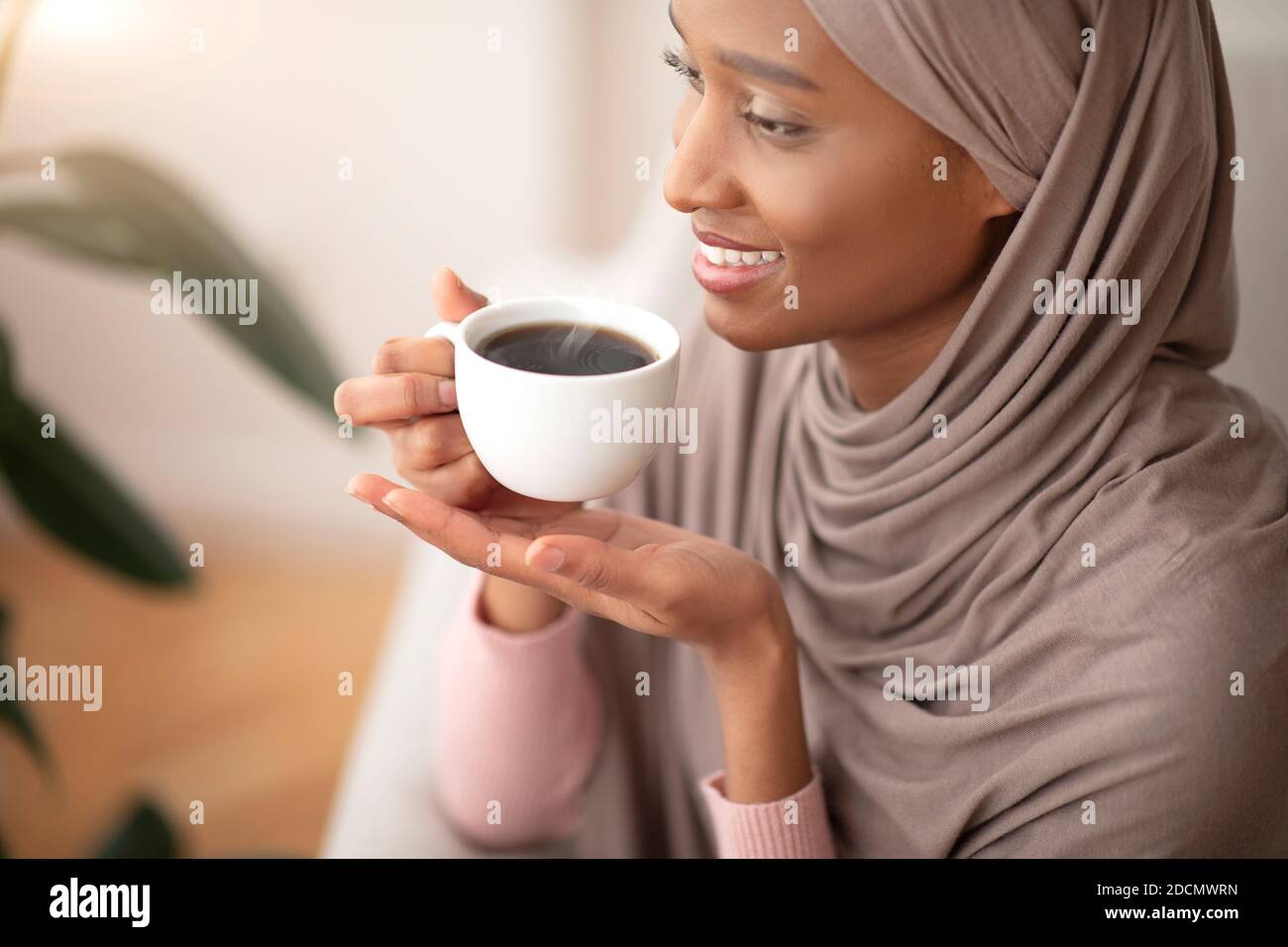 Happy morning. Happy Muslim woman in traditional hijab drinking strong ...
