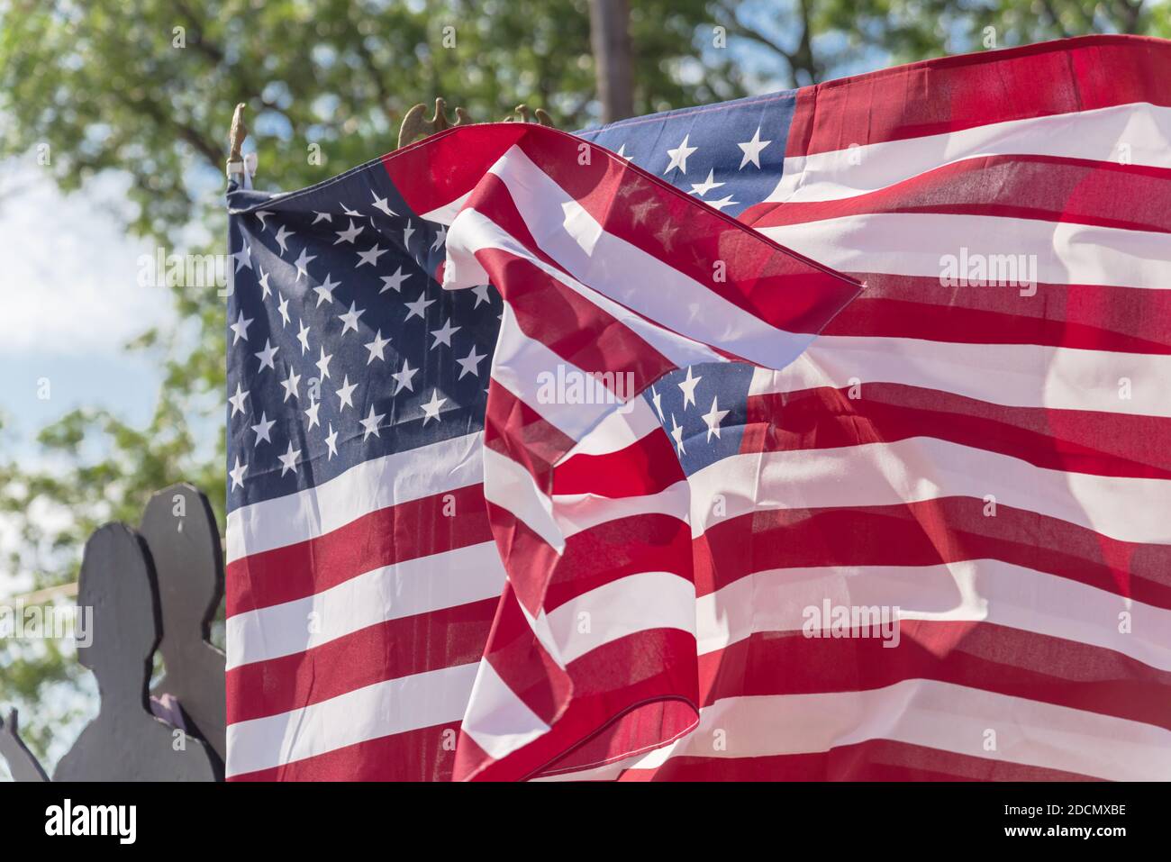 Looking up waving American flags with green trees background at a ...