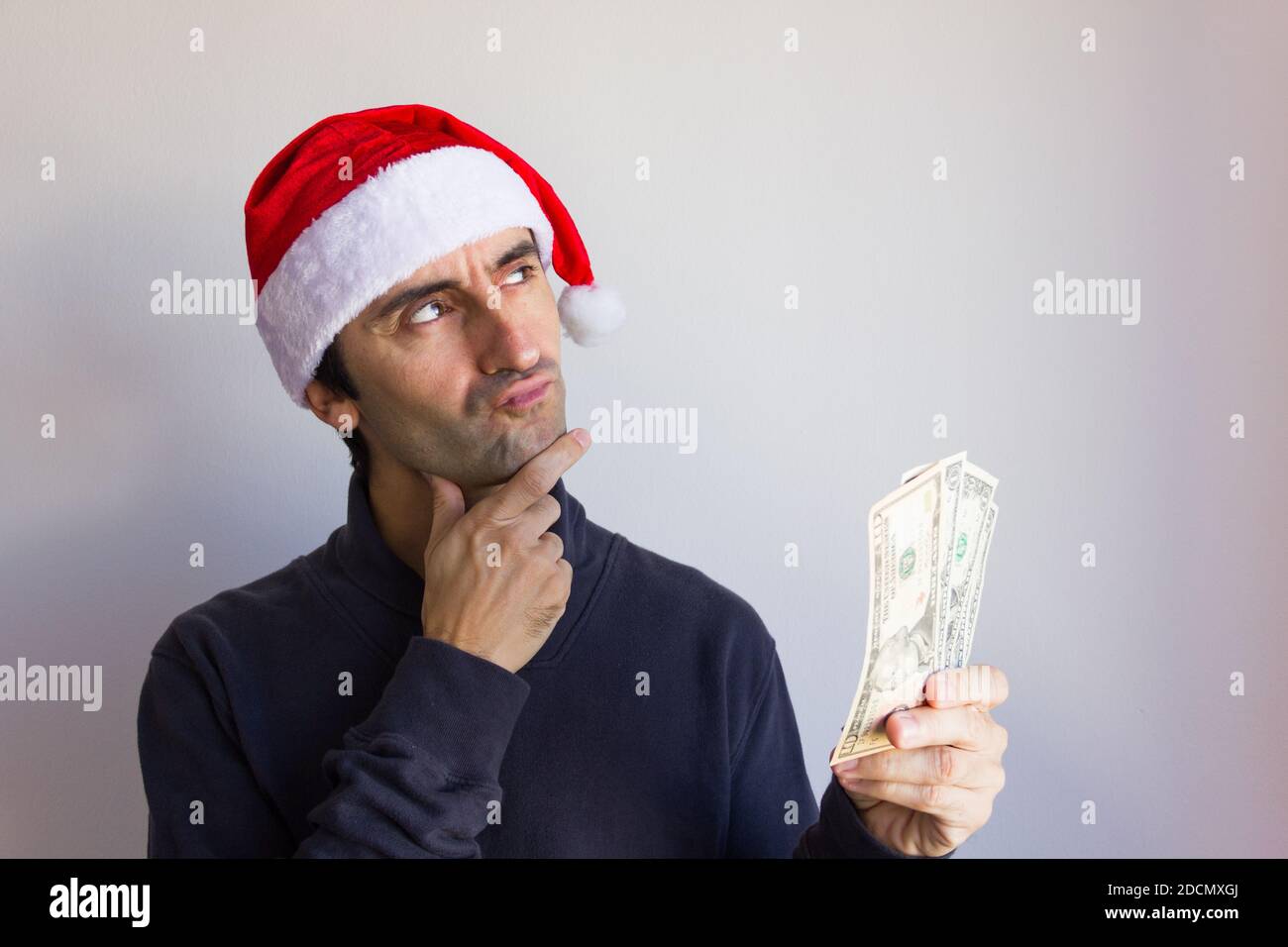 Positive thinking man with Santa red hat holding dollar bills over ...