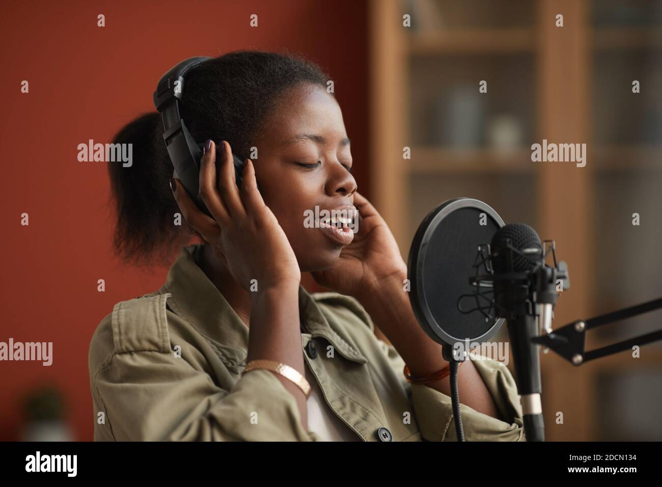 Portrait of talented African-American woman singing to microphone and ...
