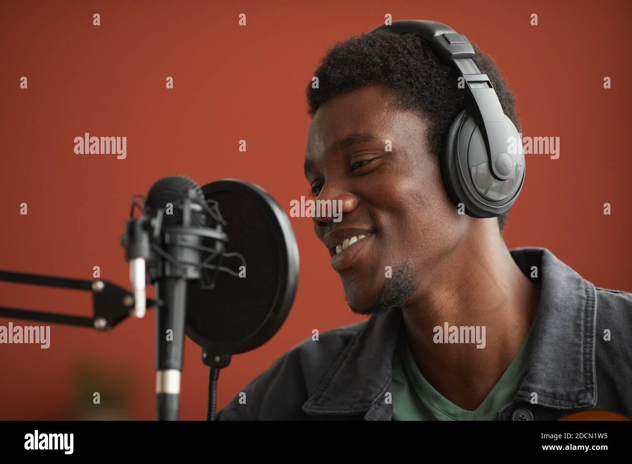 Close up portrait of smiling African-American man singing to microphone ...