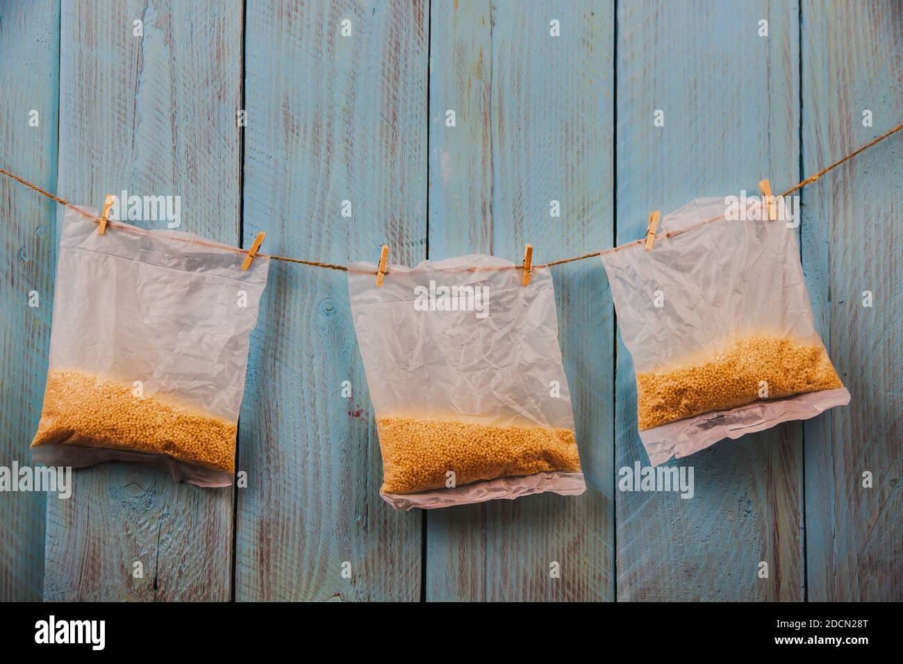 Millet in packaging hanging on the rope against blue rustic wooden ...