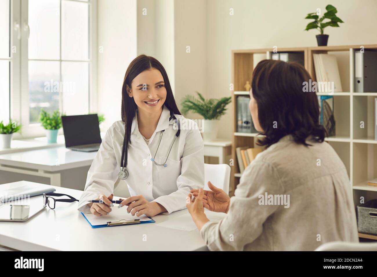 Young smiling doctor therapist listening to patients complaints in ...