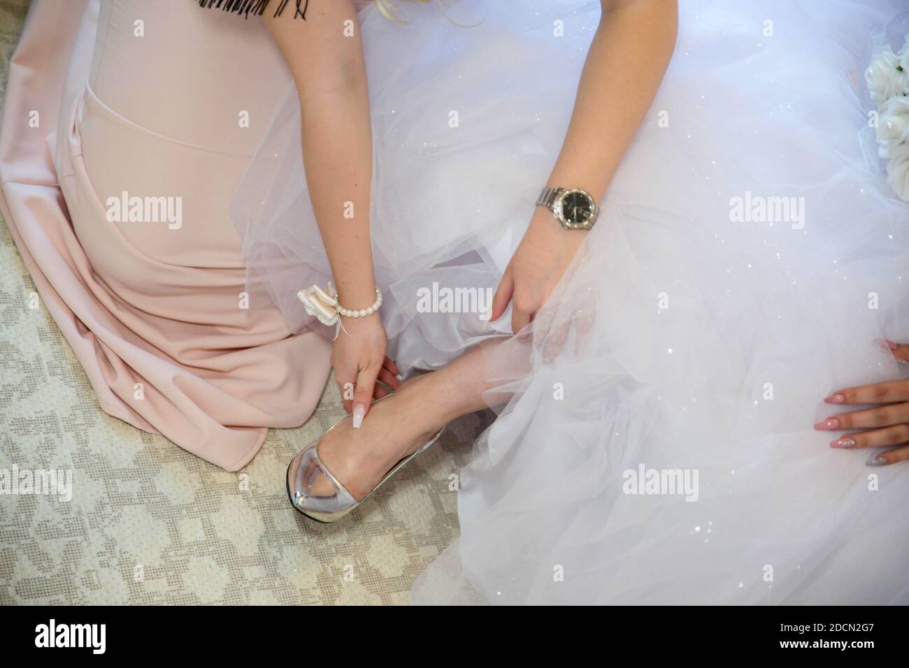 A top view closeup of the bride dressed in her bridal dress putting on ...