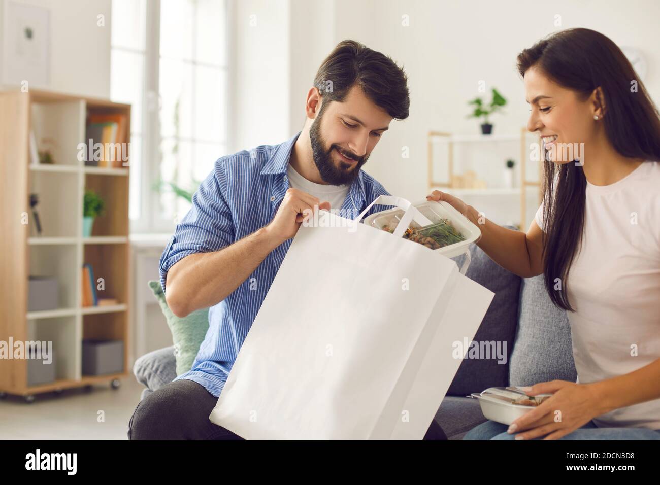 Man and a woman unpack a package of food delivered to them by the ...