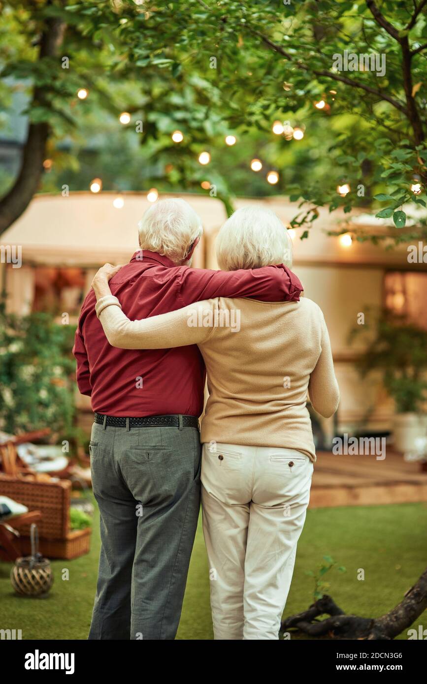 Back view of senior married couple looking at their campervan and ...