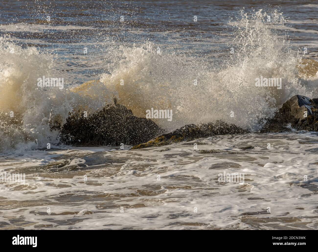An ocean wave breaking over rocks. A fast shutter speed was used to ...