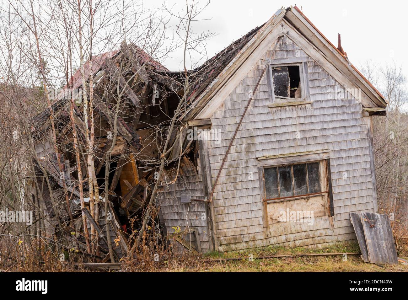 Old abandoned house that has collapsed. The windows are broken & the roof has fallen in. The ...