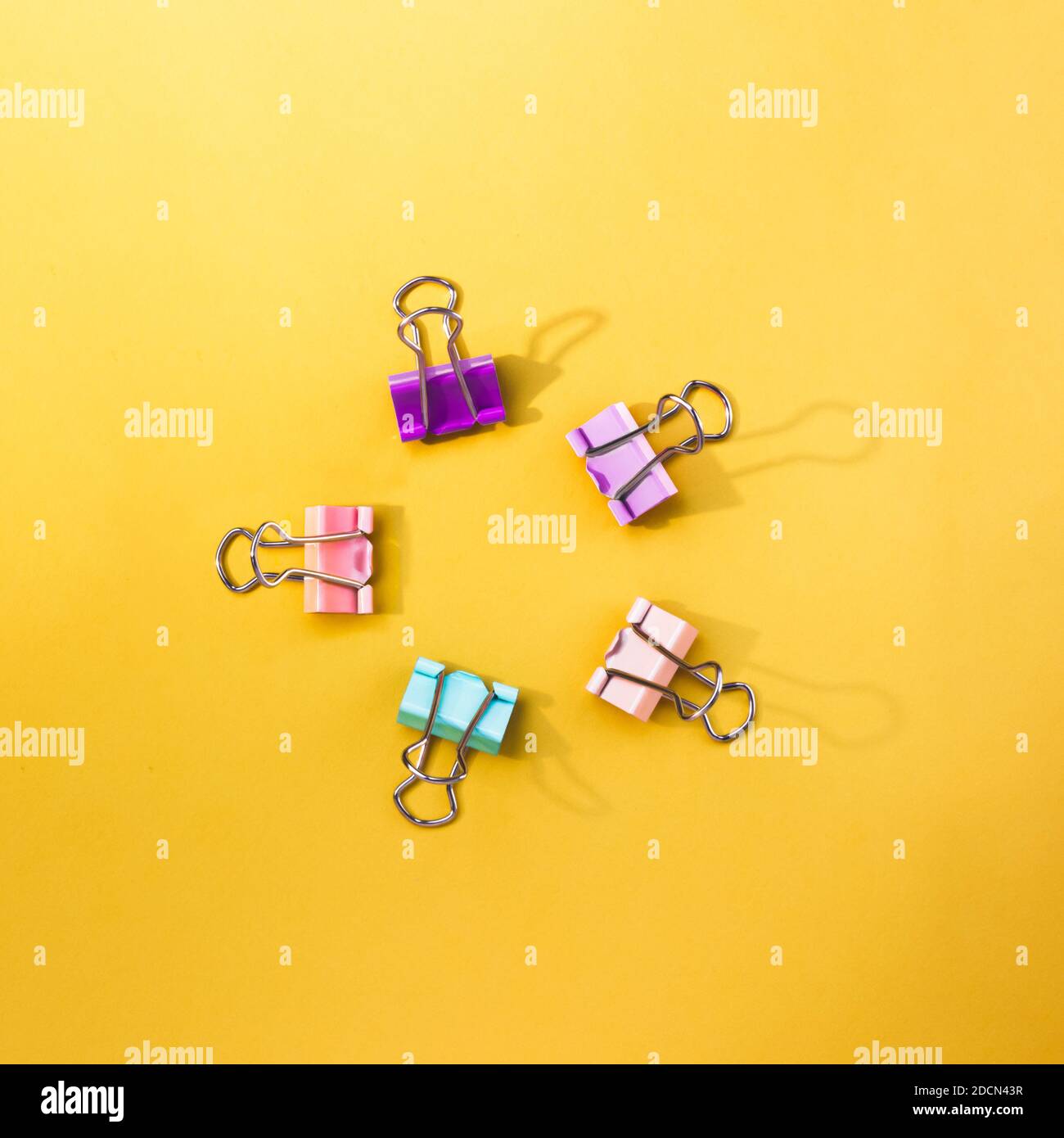 Five colorful paper clips forming circle on a yellow backdrop. Good ...