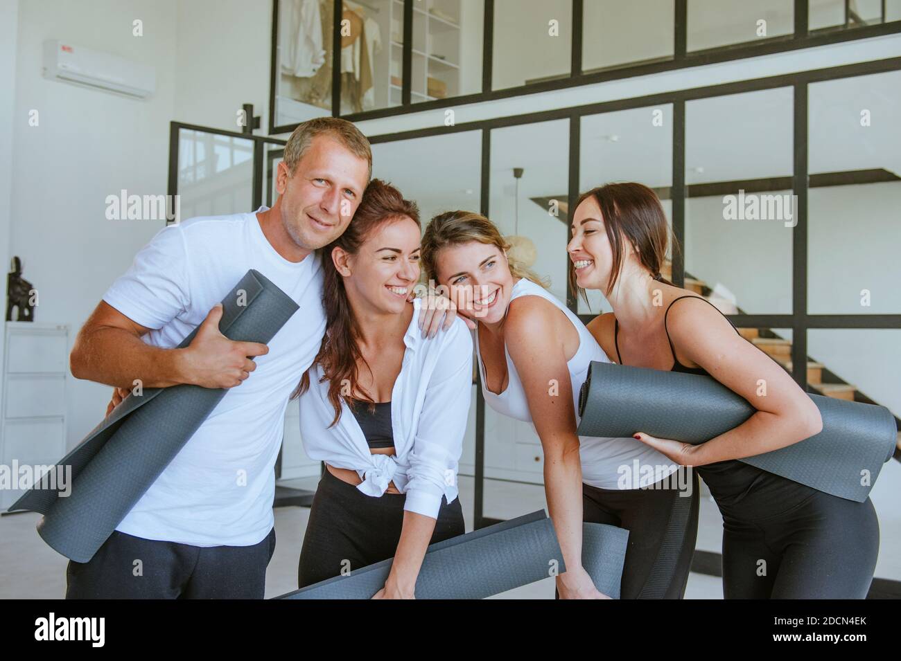 Smiling young people having fun after yoga class indoor. Group of happy ...