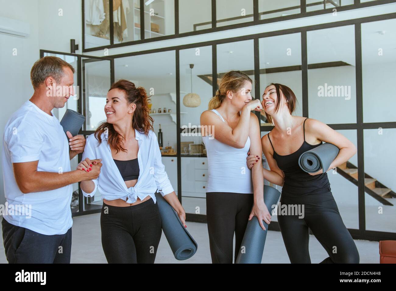 Smiling young people having fun after yoga class indoor. Group of happy ...
