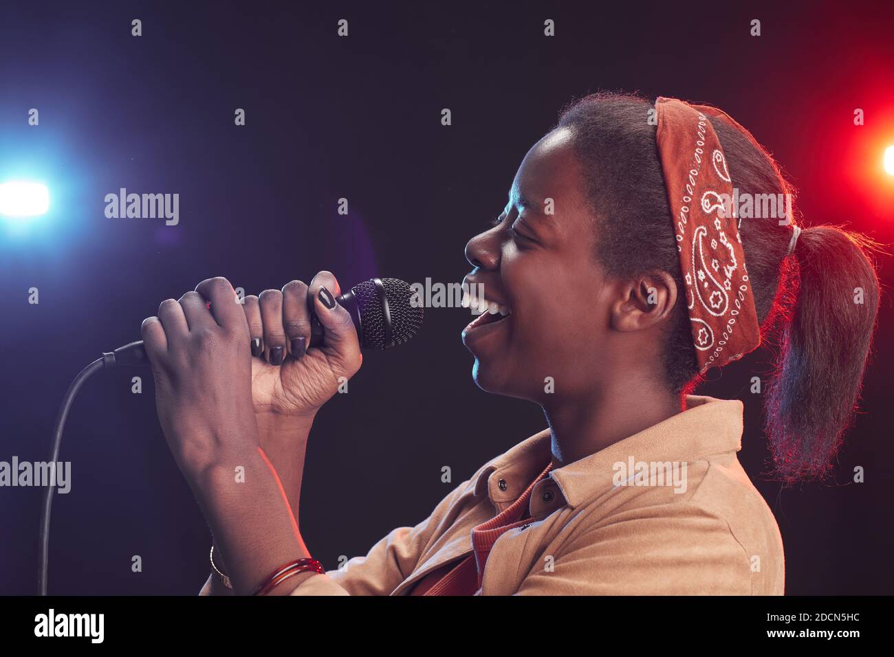 Side view portrait of young African-American woman singing to ...