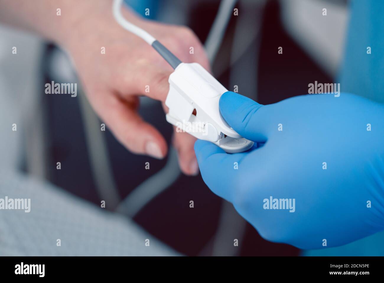 Nurse in hospital putting blood pressure sensor on patient's finger ...