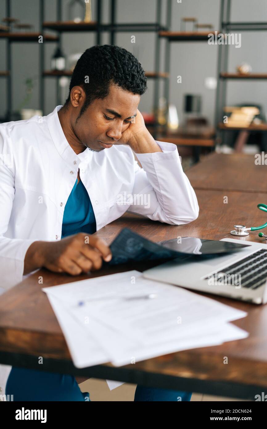 Side view of ponder African American black male doctor in white coat ...