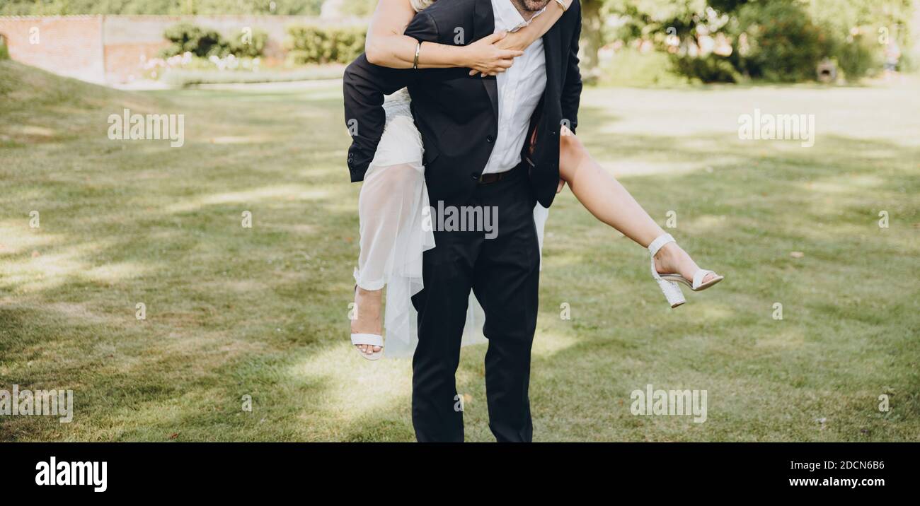 Groom is carrying the bride on his back, bridal couple having fun ...