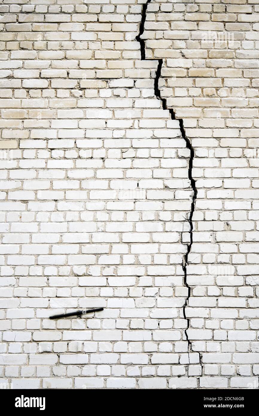 a large long and wide crack in a white brick wall Stock Photo - Alamy