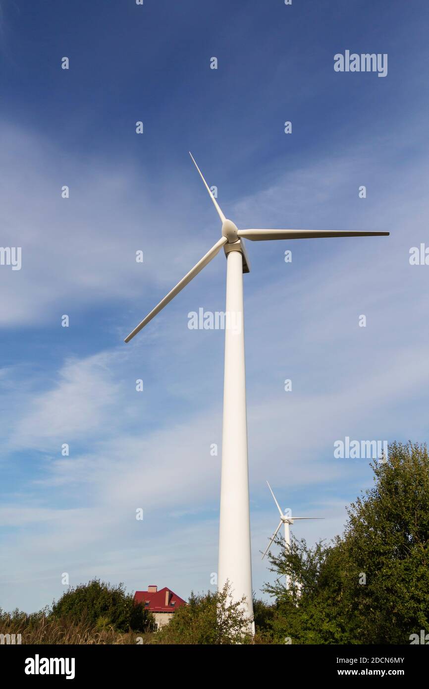 Windmill for electricity among the trees with the house Stock Photo - Alamy