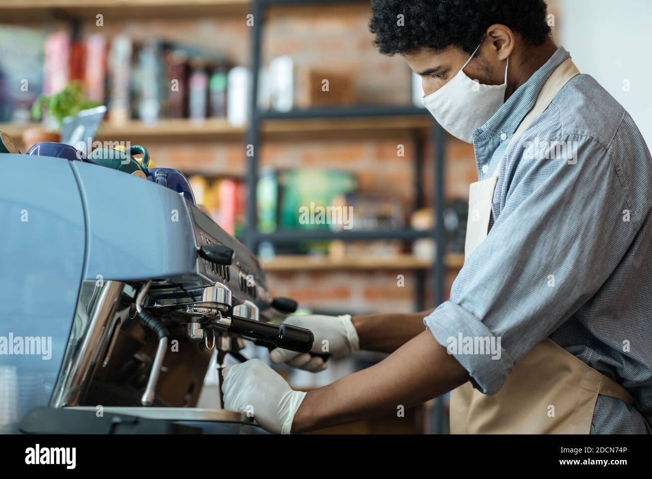 Professional barista works with equipment in cafe during social ...