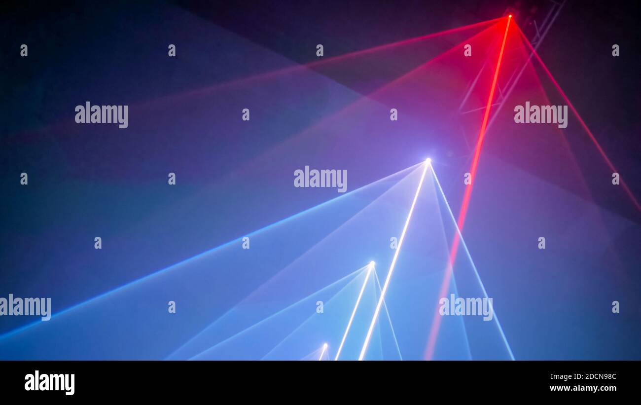 Bright laser show installation with color rays or beams in dark room ...