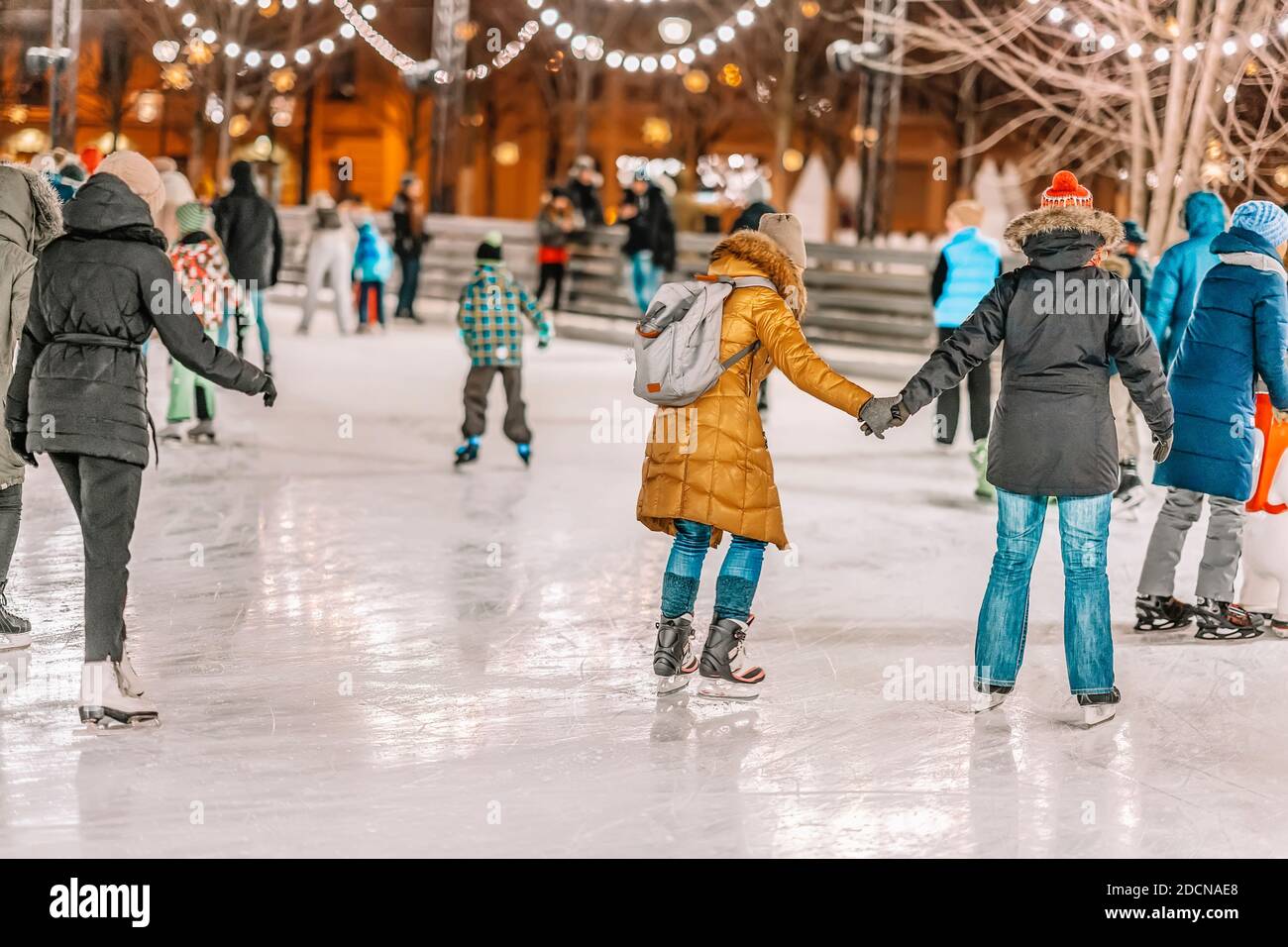 Happy couples, friends ice skate on a skating rink in a city park ...