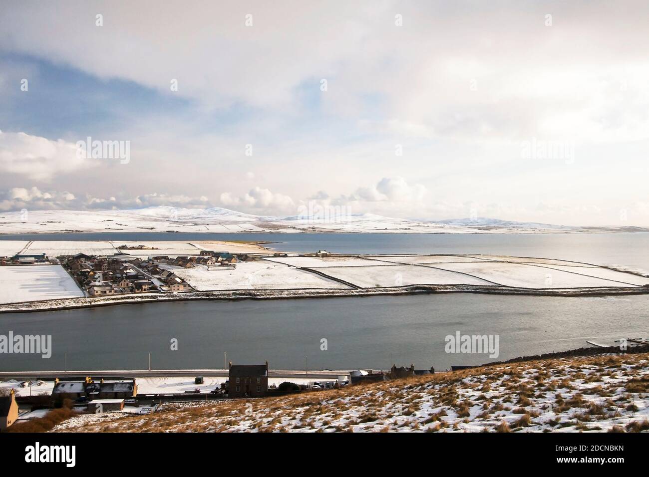 Aerial view from top of the hill with houses under snow and sea in ...