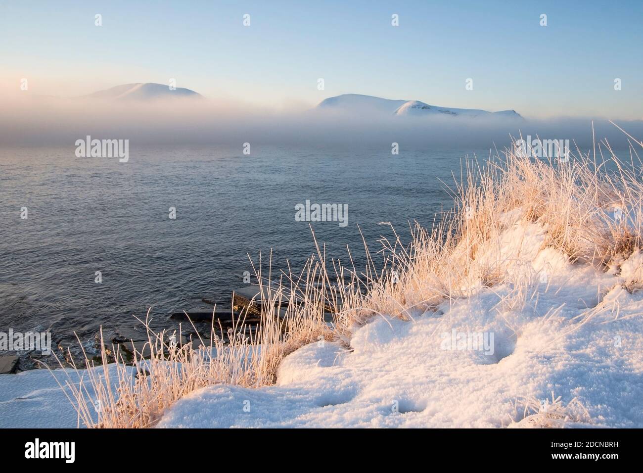 Cliffs with grass under the snow and white hills in winter day scene on ...